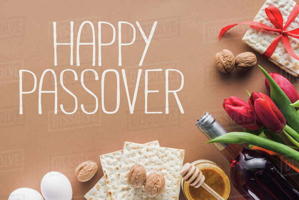 Top view of happy Passover greeting and matzah on brown, Passover tale ...