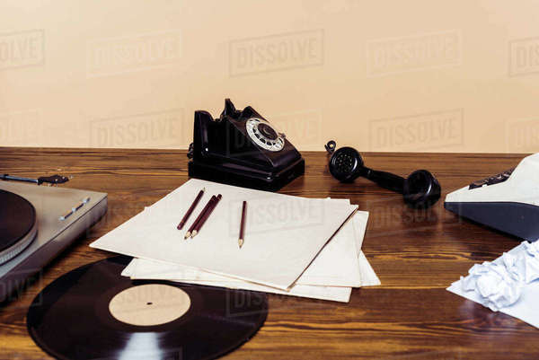 Rotary phone, vinyl disc, record player and typewriter on wooden table ...