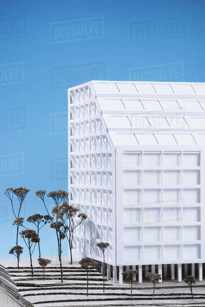 Close up view of white building model with miniature trees on blue ...