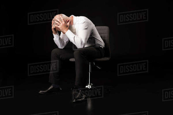 Full-length shot of man in a suit sitting on a chair and holding his ...