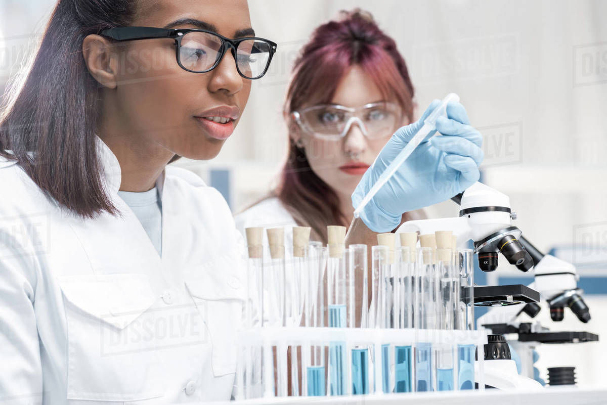 Professional young scientists working with microscope and test tubes in ...