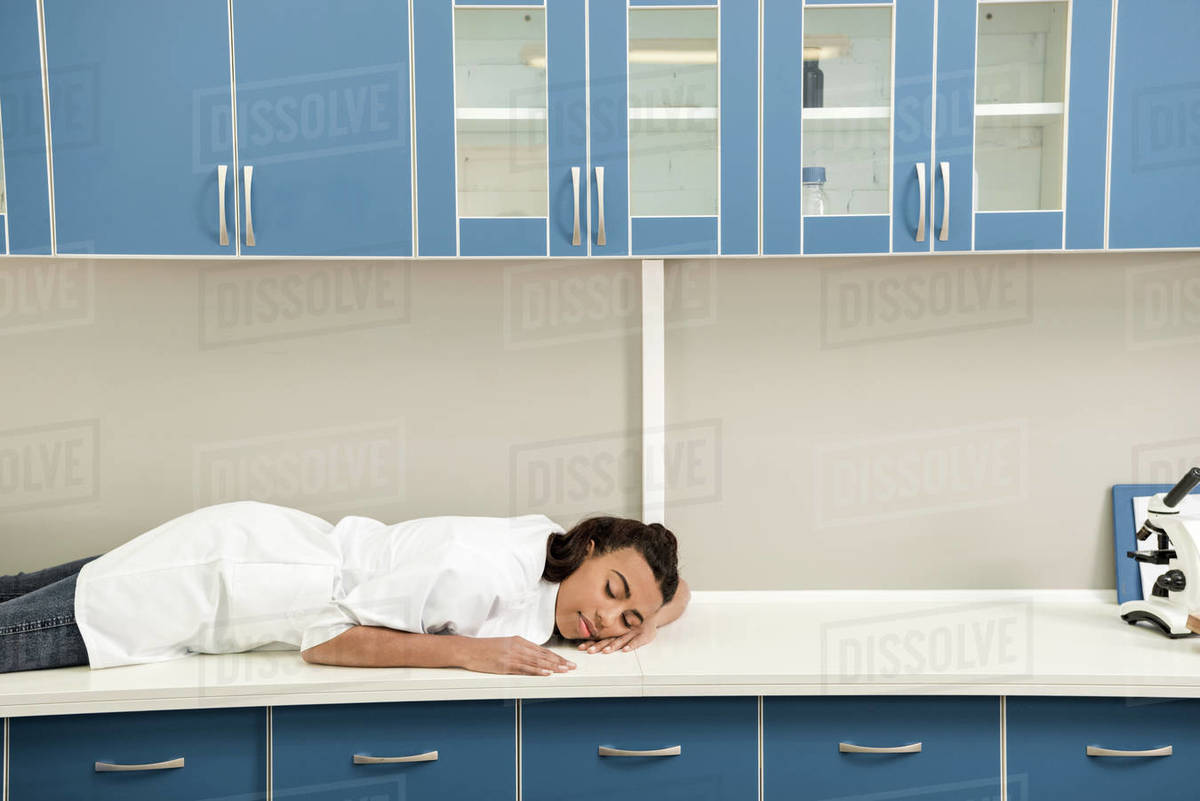 young tired girl scientist sleeping on table in chemical laboratory ...