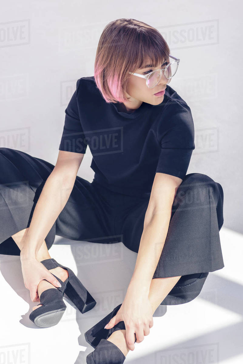 Overhead view of stylish girl sitting in black clothes on white ...