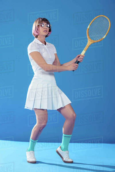 Female tennis player standing in pose with tennis racket on blue ...