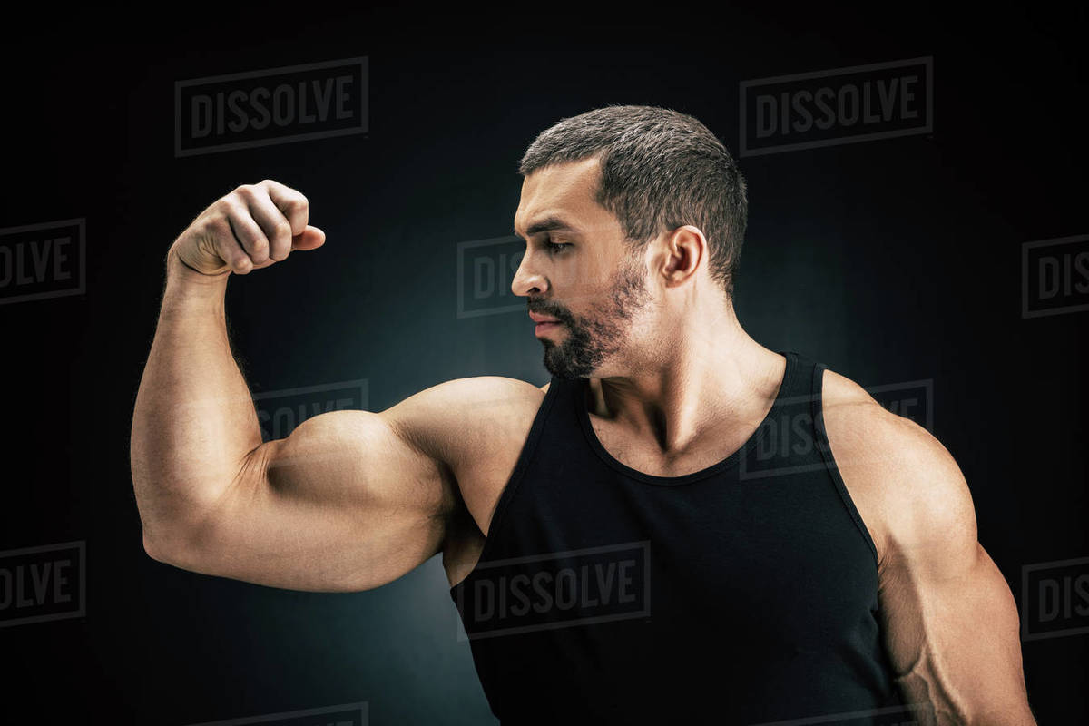 Portrait of strong man showing muscles isolated on black - Royalty-free ...