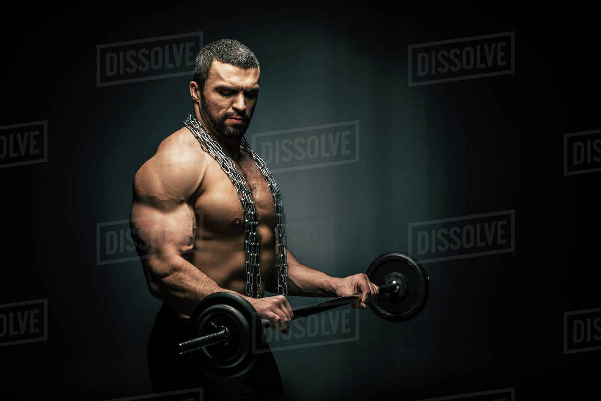 Side view of athletic man with metal chain on neck weightlifting ...