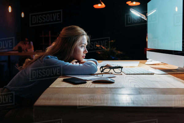 Side view of exhausted businesswoman looking at computer screen at ...