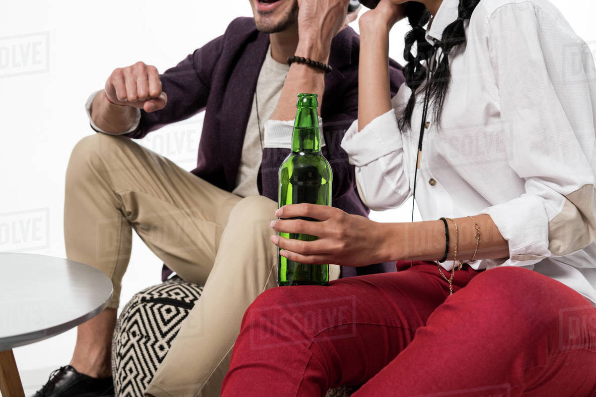 Cropped shot of young couple sitting together and drinking beer ...