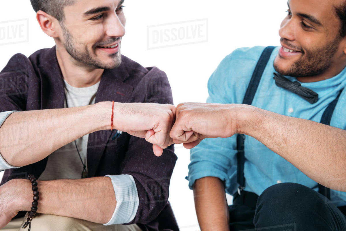 young multiethnic friends smiling and doing fist bump isolated on white ...