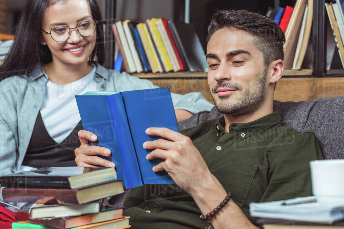 Smiling young couple of students reading books together - Royalty-free ...