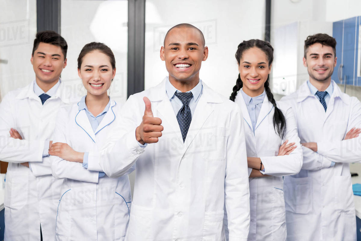 Team of smiling professional doctors standing together, while their ...
