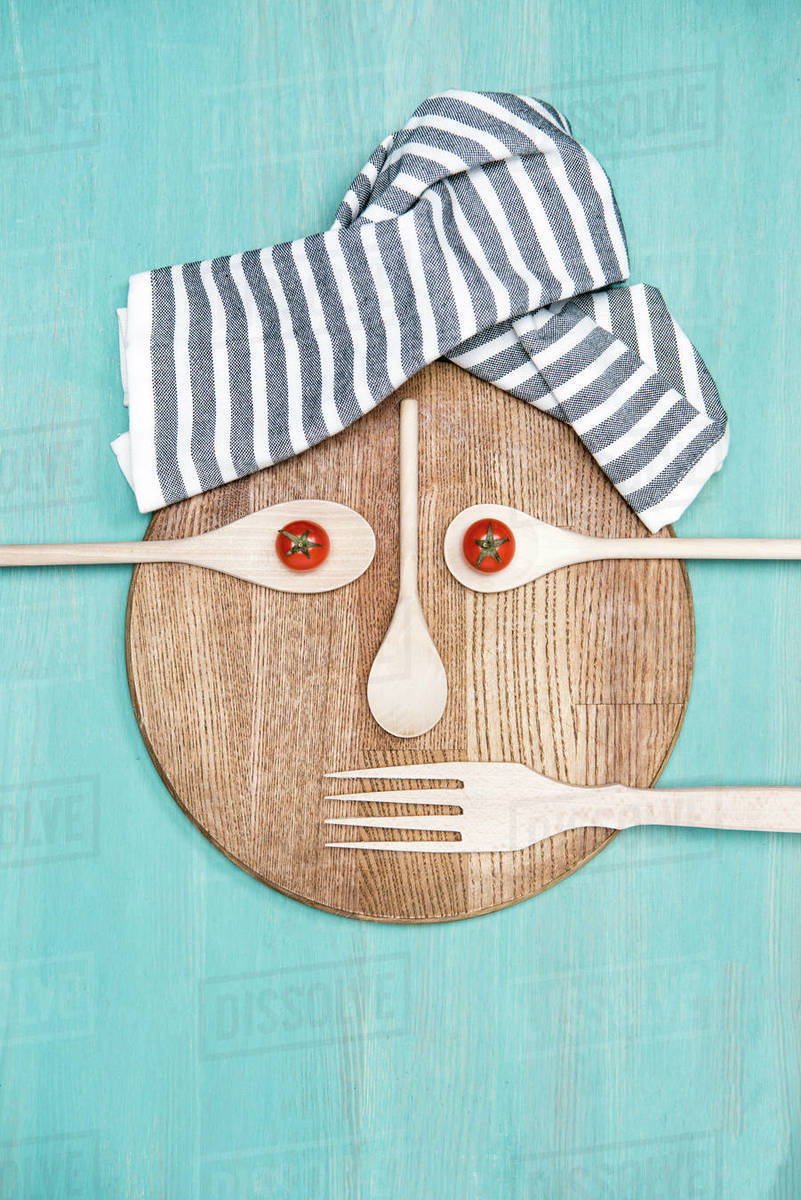 Top view of wooden cooking utensils with tomatoes in form of face on ...