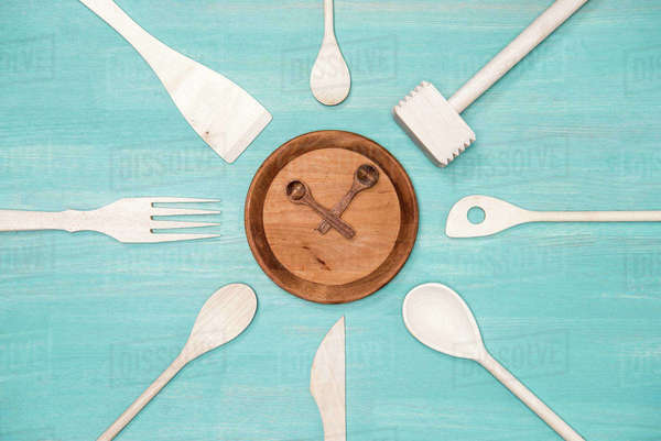 Top view of various wooden kitchen utensils with clock symbol on plate ...