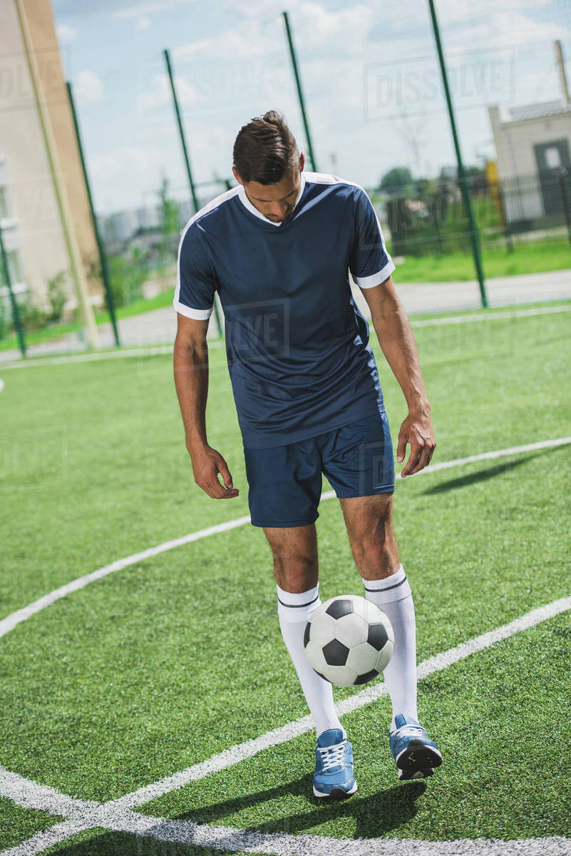 Athletic soccer player training with ball on soccer pitch - Royalty ...