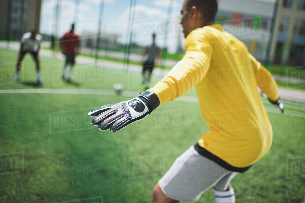 Side view of african american goalkeeper standing on soccer pitch ...