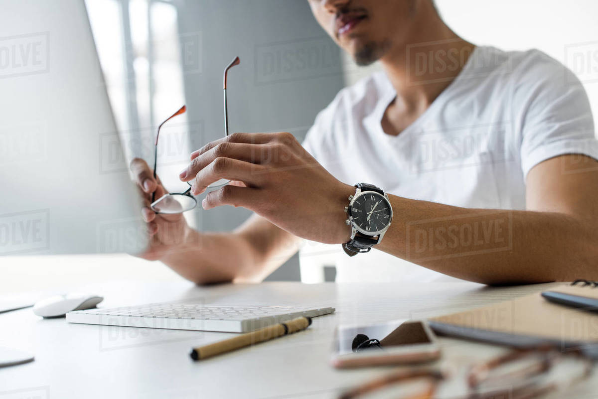 Cropped shot of young man holding eyeglasses at workplace - Stock Photo ...