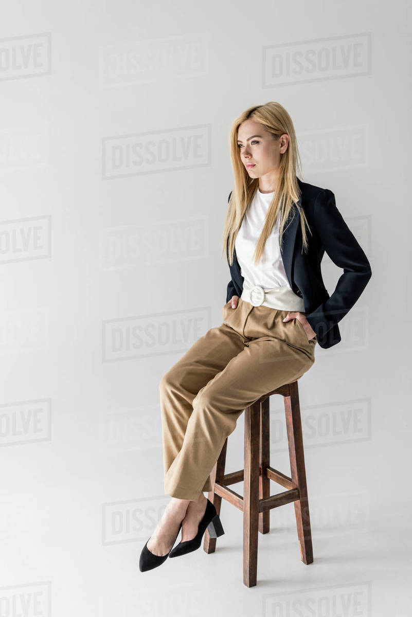 Full length view of beautiful stylish blonde girl sitting on chair and ...