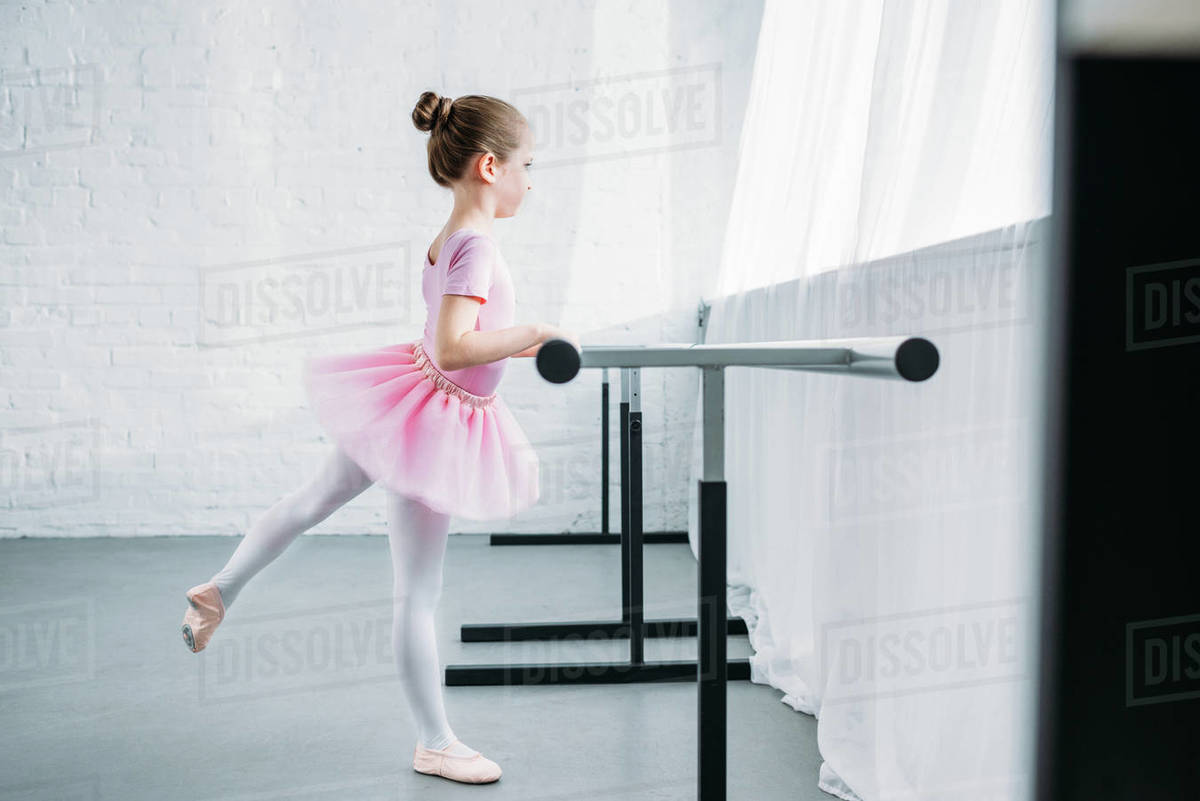 Side view of child in pink tutu practicing ballet in studio - Royalty ...