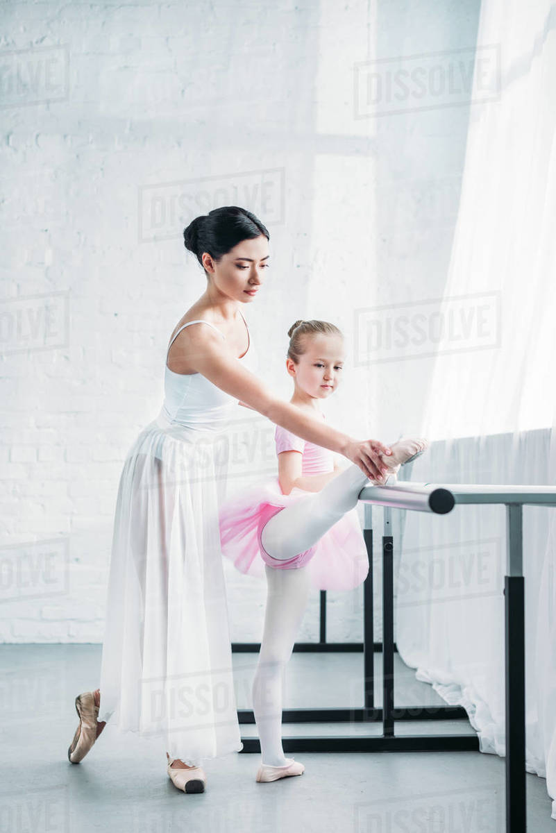 Adorable child in pink tutu stretching while practicing ballet with ...