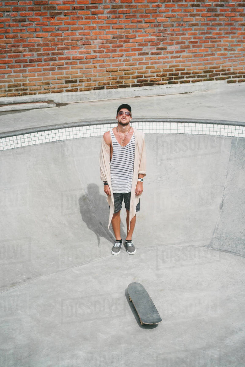High angle view of handsome skater standing in pool at skatepark ...