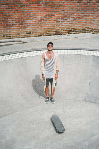 High angle view of handsome skater standing in pool at skatepark ...