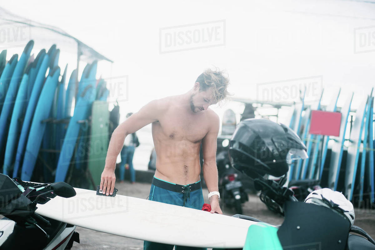 Handsome surfer cleaning surfboard in Bali, Indonesia - Royalty-free ...