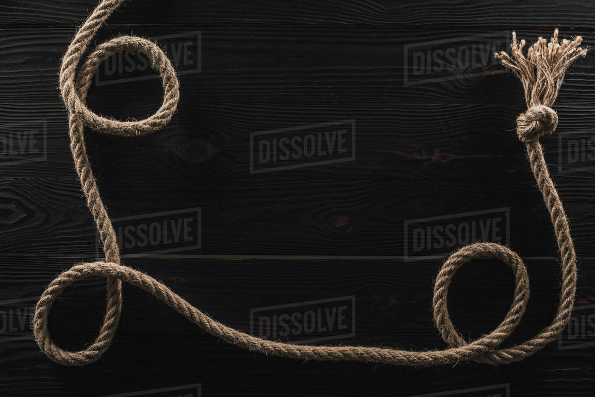 Top view of brown nautical rope with knot on dark wooden surface ...