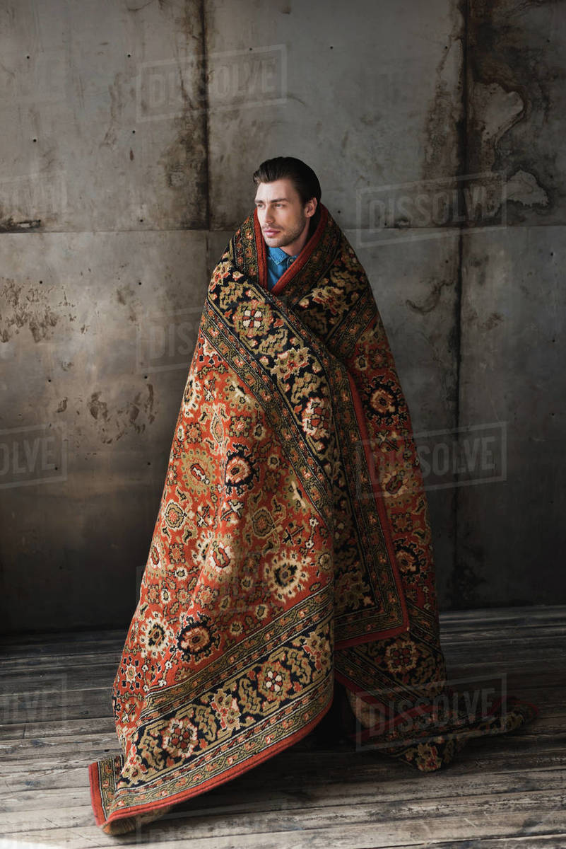 Handsome young man covered in rug in front of concrete wall - Royalty ...