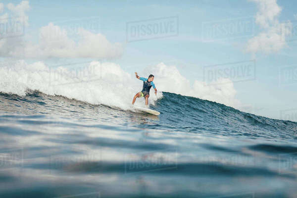 Side view of young sportsman in wetsuit having fun on surfboard on ...