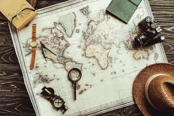 Flat lay with straw hat, map, magnifying glass, compass and retro photo ...