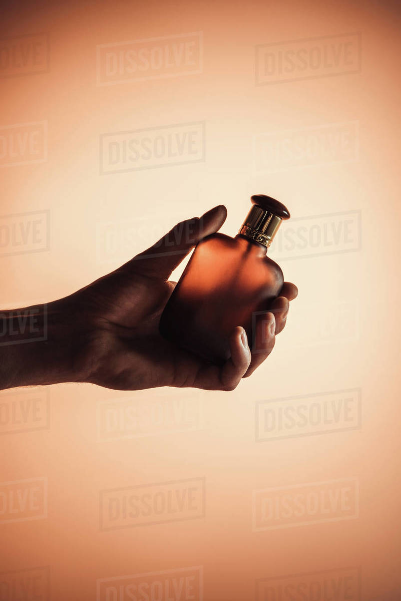 Cropped view of male hand with perfume, isolated on orange - Royalty ...