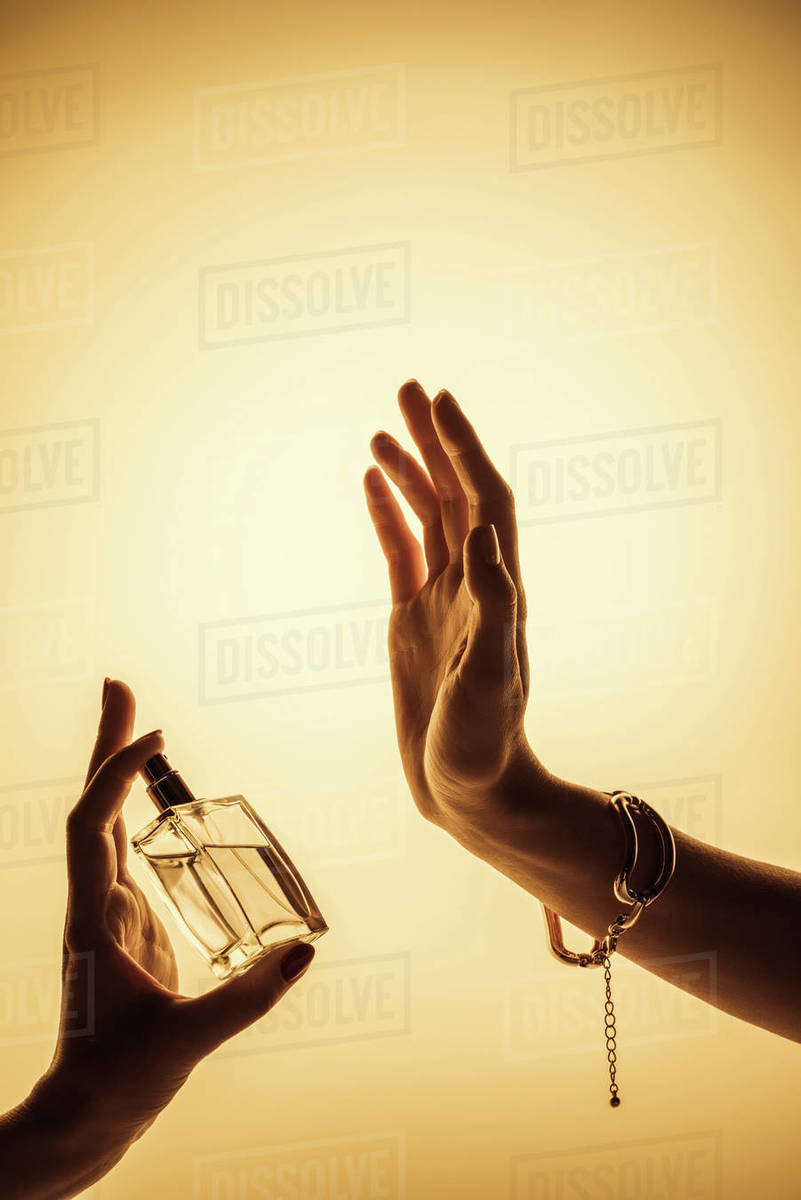 Cropped view of woman spraying perfume on hand to feel fragrance ...
