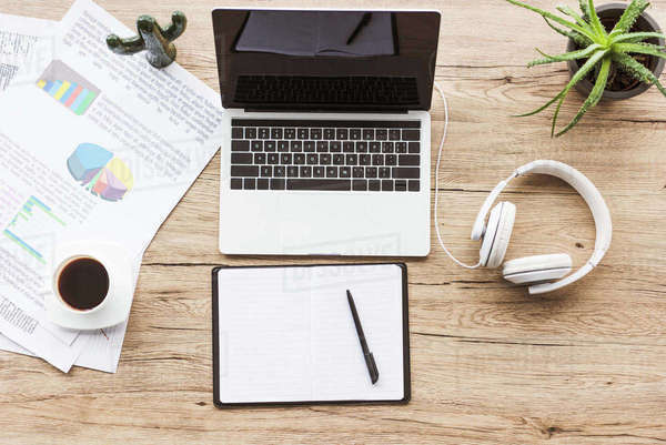 Flat lay with laptop with blank screen, empty notebook, headphones and ...