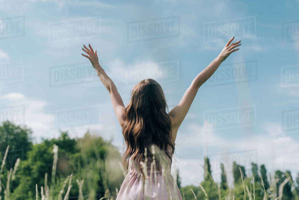 Back view of woman in stylish dress with outstretched arms standing in ...
