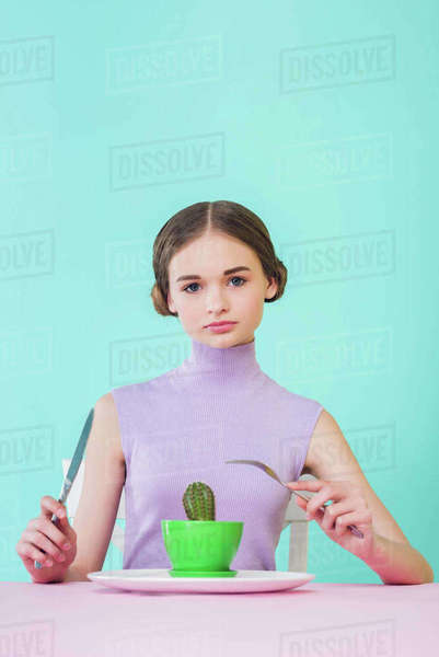 stylish female teenager eating cactus with fork and knife, diet concept ...