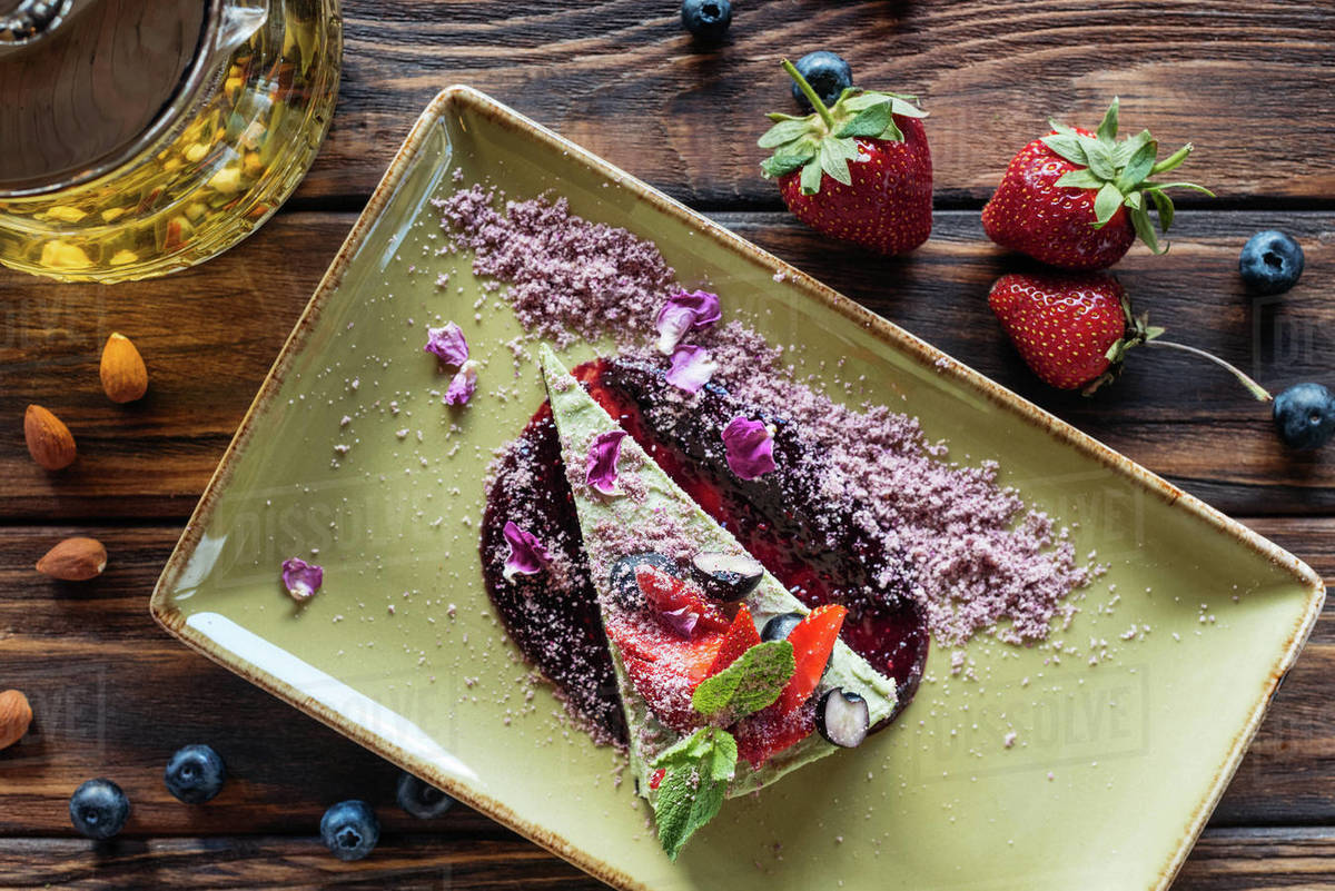 Top view of arranged vegetarian dessert with berries on plate, almonds ...