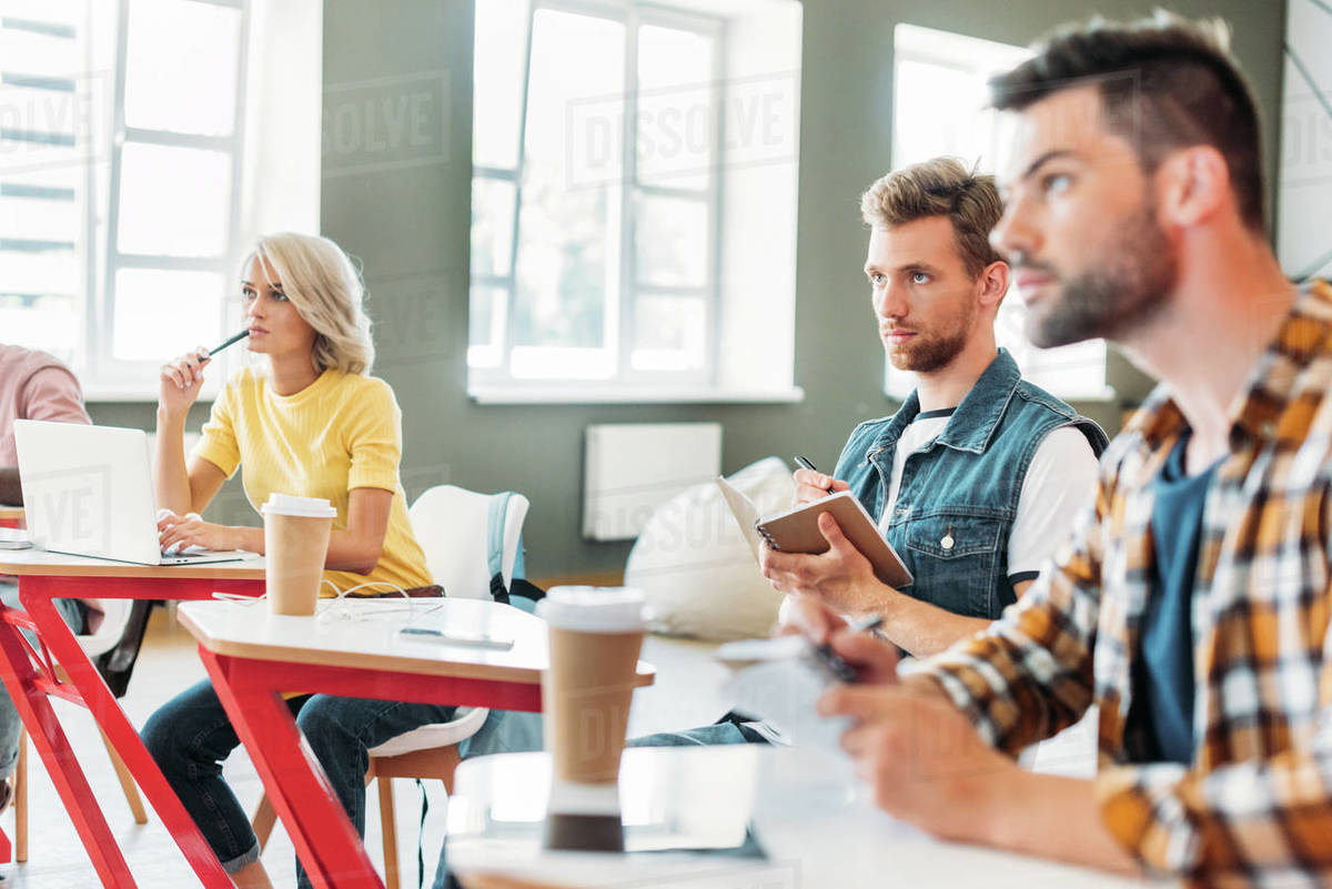 Focused young students listening lecture together - Stock Photo - Dissolve