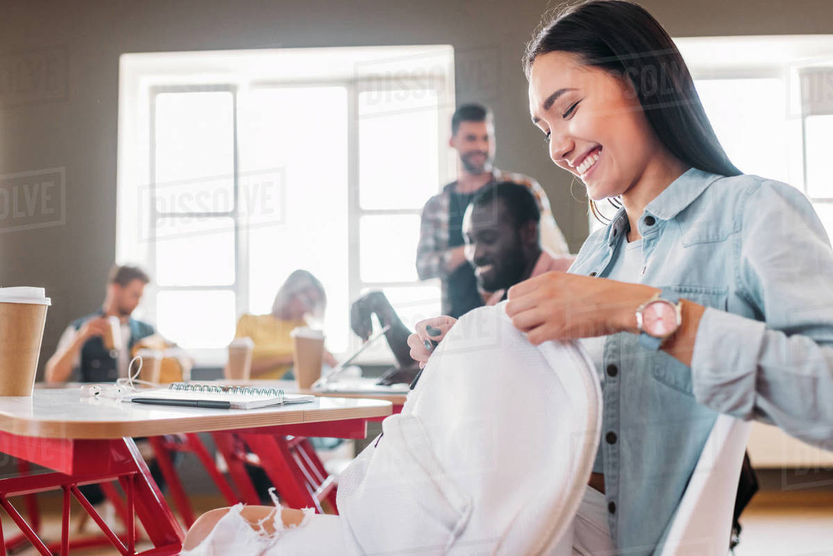 Happy young student girl opening backpack at classroom with blurred ...