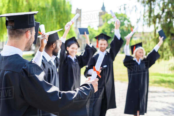Young happy students celebrating graduation together on college square ...