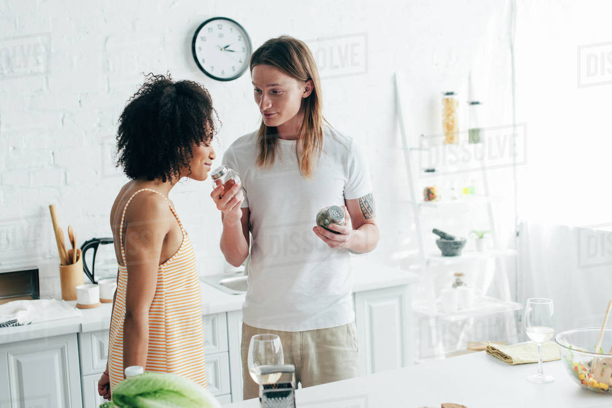 Young man with tattooed hand giving girlfriend to sniff spices at ...
