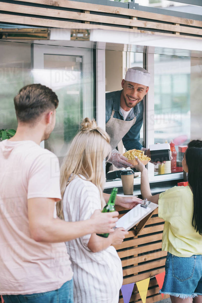 Smiling chef giving french fries to girl from food truck - Stock Photo ...
