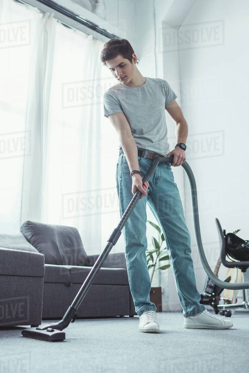 Teenager cleaning floor with vacuum cleaner - Stock Photo - Dissolve