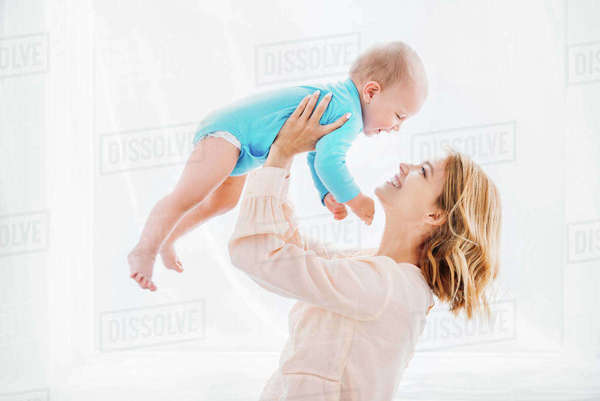 Side view of mother raising up her happy child - Royalty-free Stock ...