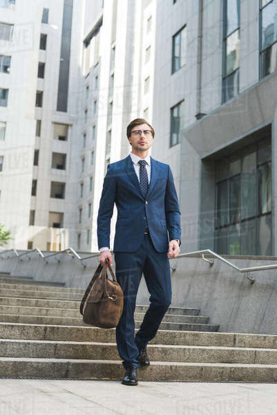 Handsome young businessman in stylish suit with briefcase in business ...