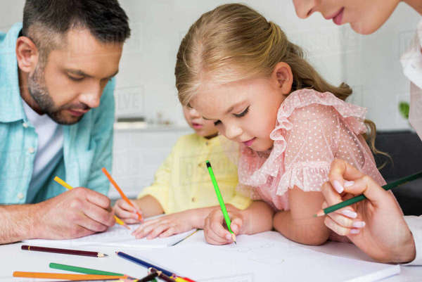 Cropped shot of parents with cute little children drawing with colored ...