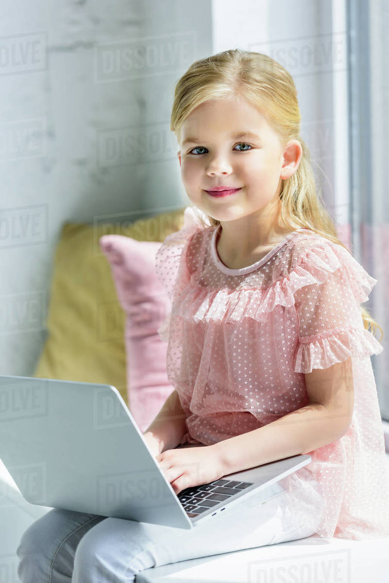 Adorable child using laptop and smiling at camera at home - Stock Photo ...