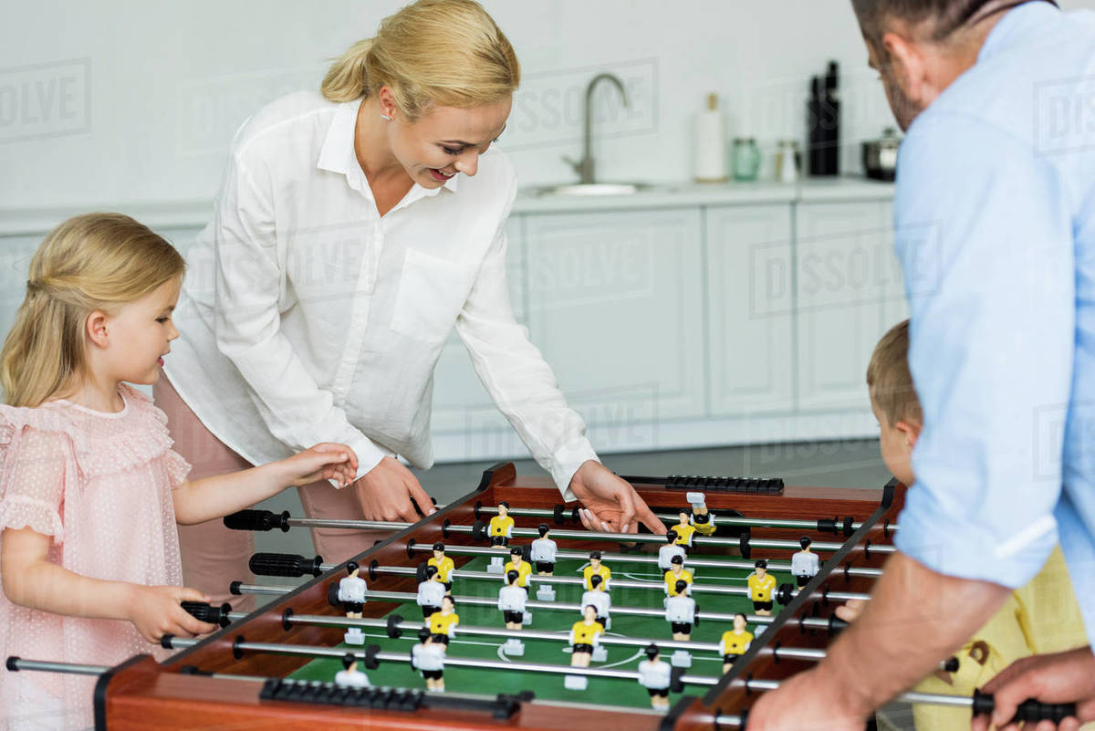 Happy family with two kids playing table football together at home ...