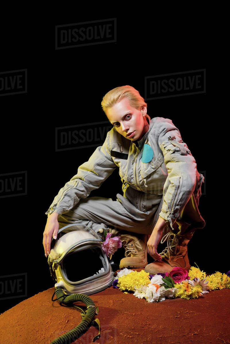 Stylish cosmonaut in spacesuit with flowers and helmet sitting on ...