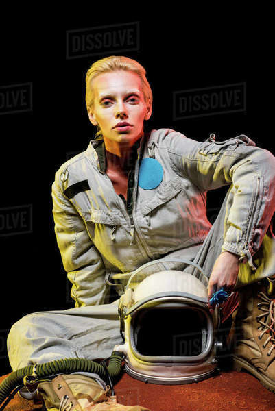 Attractive astronaut in spacesuit with helmet sitting on planet ...