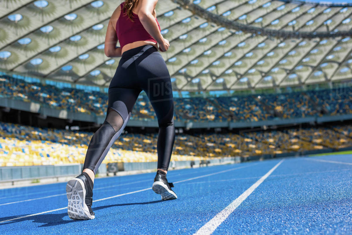 Bottom view of athletic young woman running on track at sports stadium ...